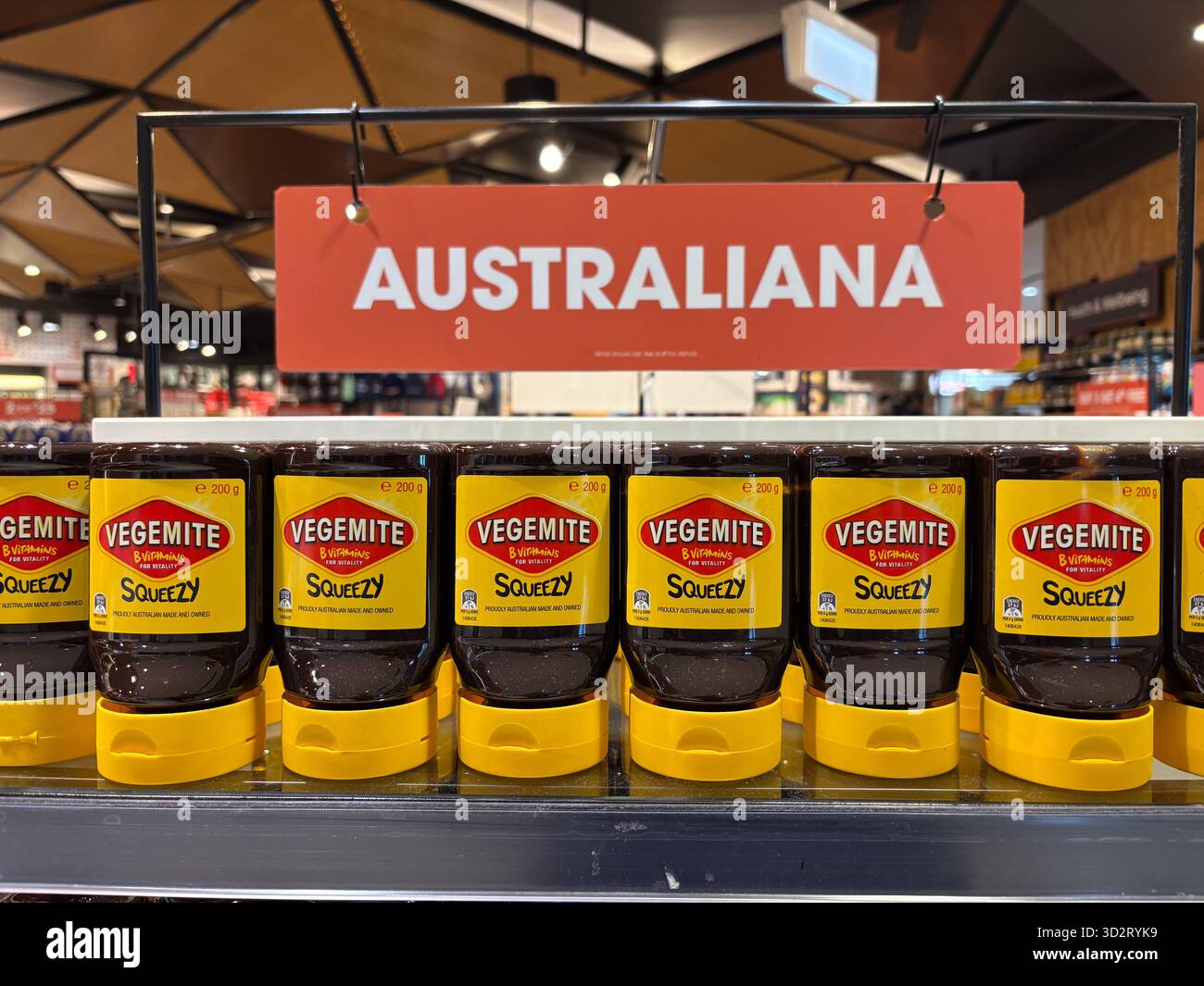 Vegemite Squeezy bottles displayed on a supermarket shelf under an ...