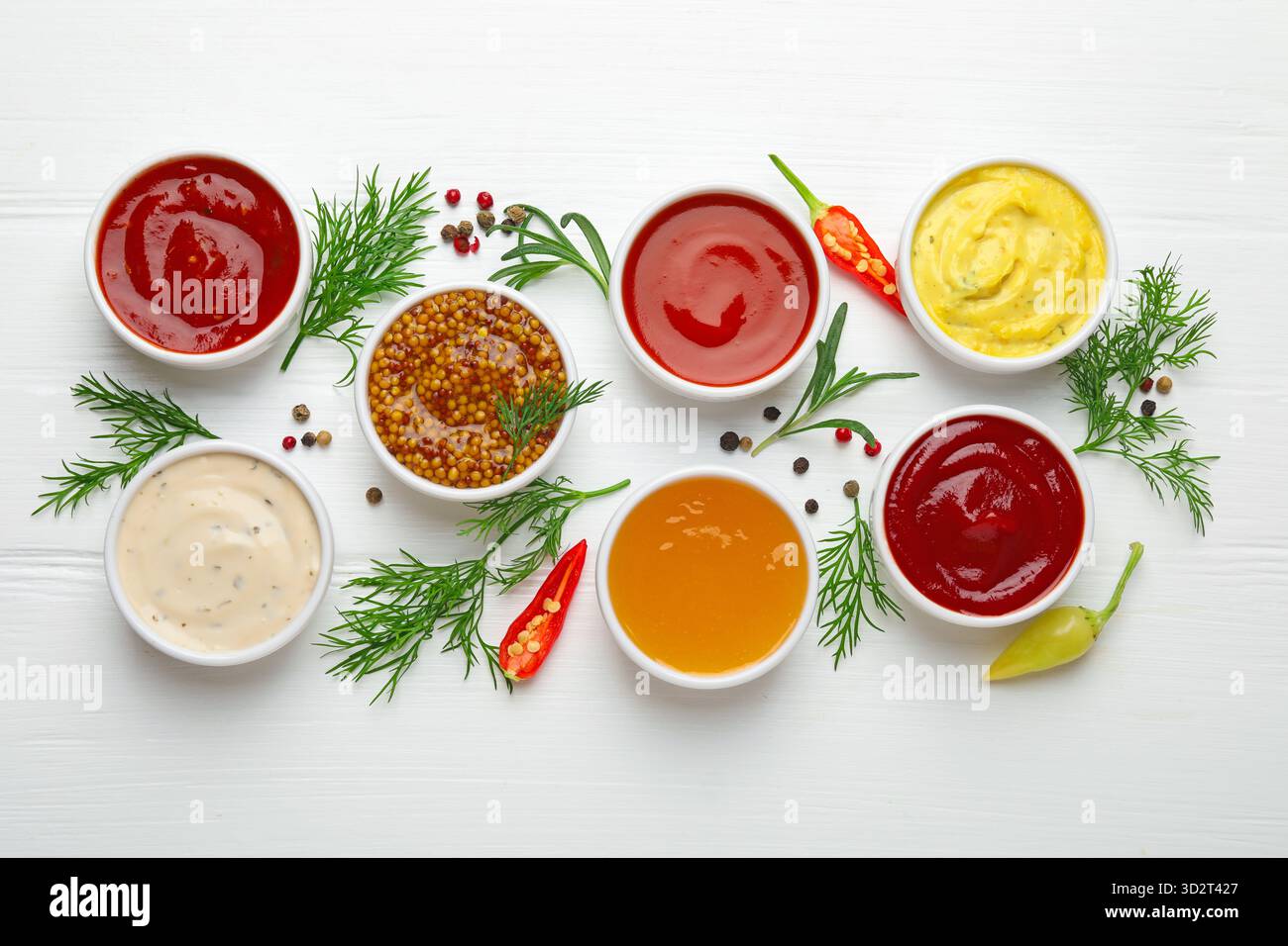 Different sauces in bowls and ingredients on white wooden table, flat ...