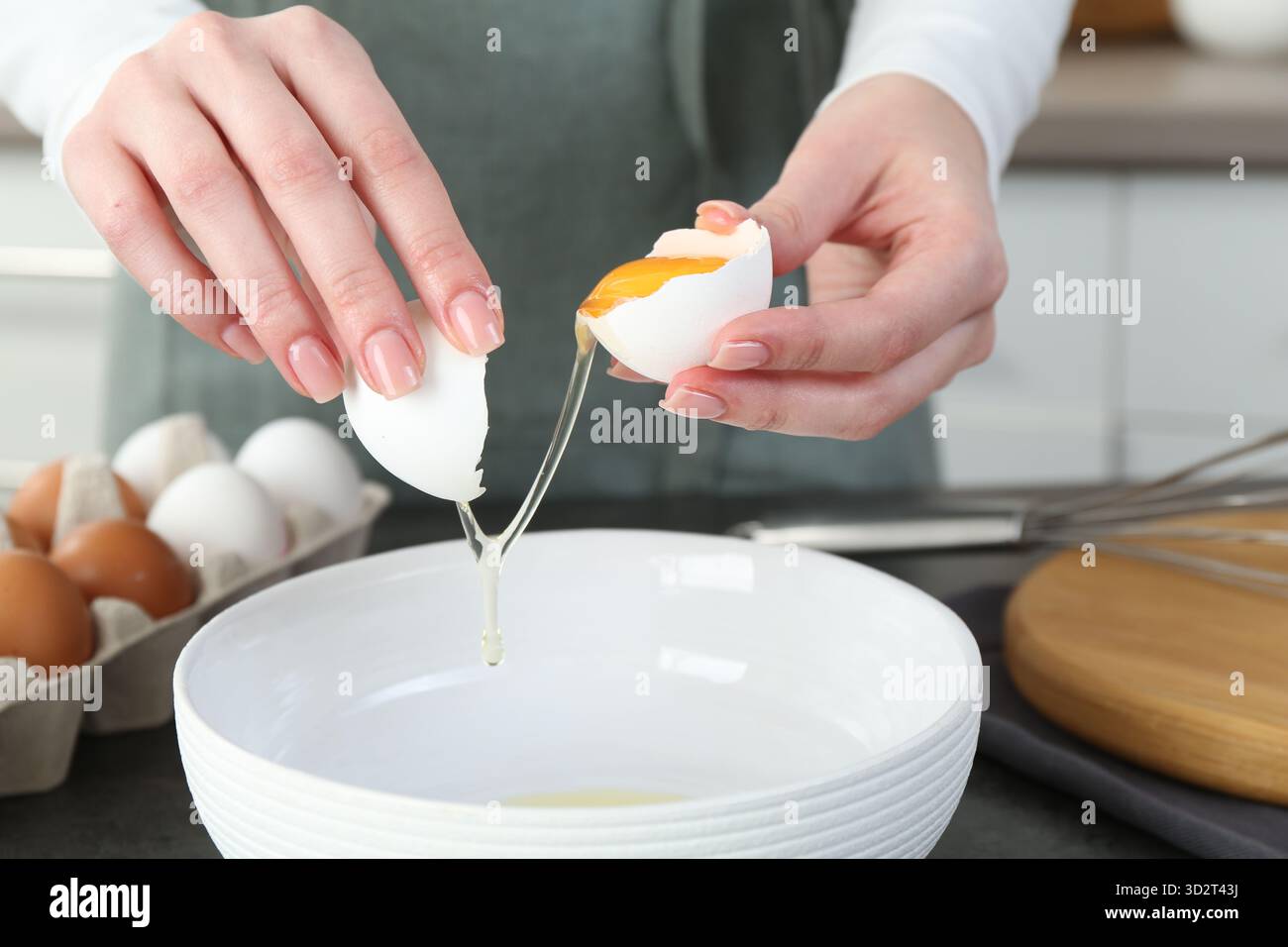Woman cracking egg into bowl at grey table in kitchen, closeup Stock ...