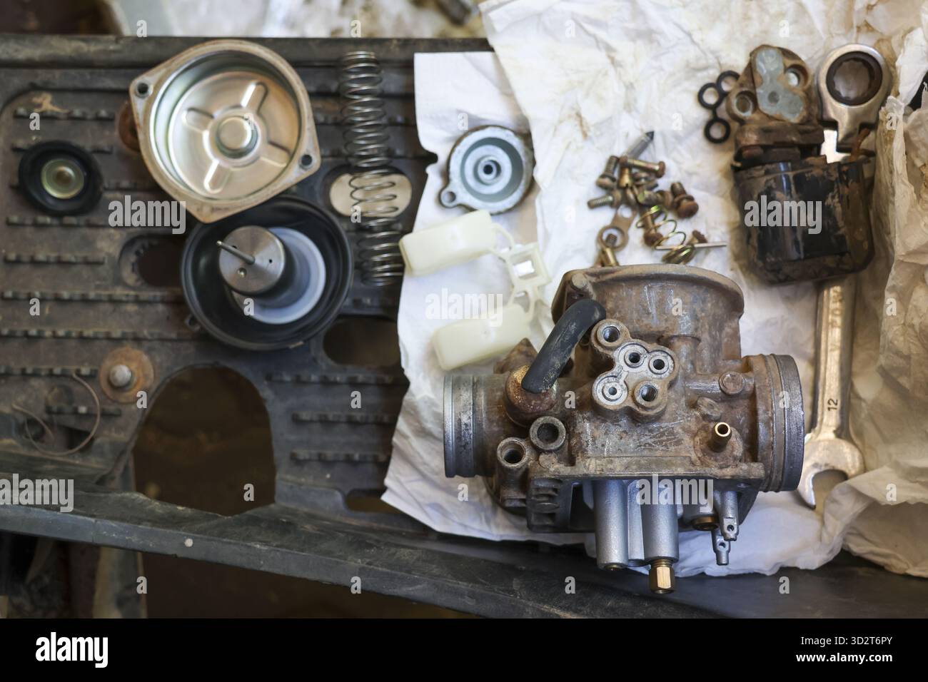 Focused carburetor repair project with disassembled motorcycle engine ...