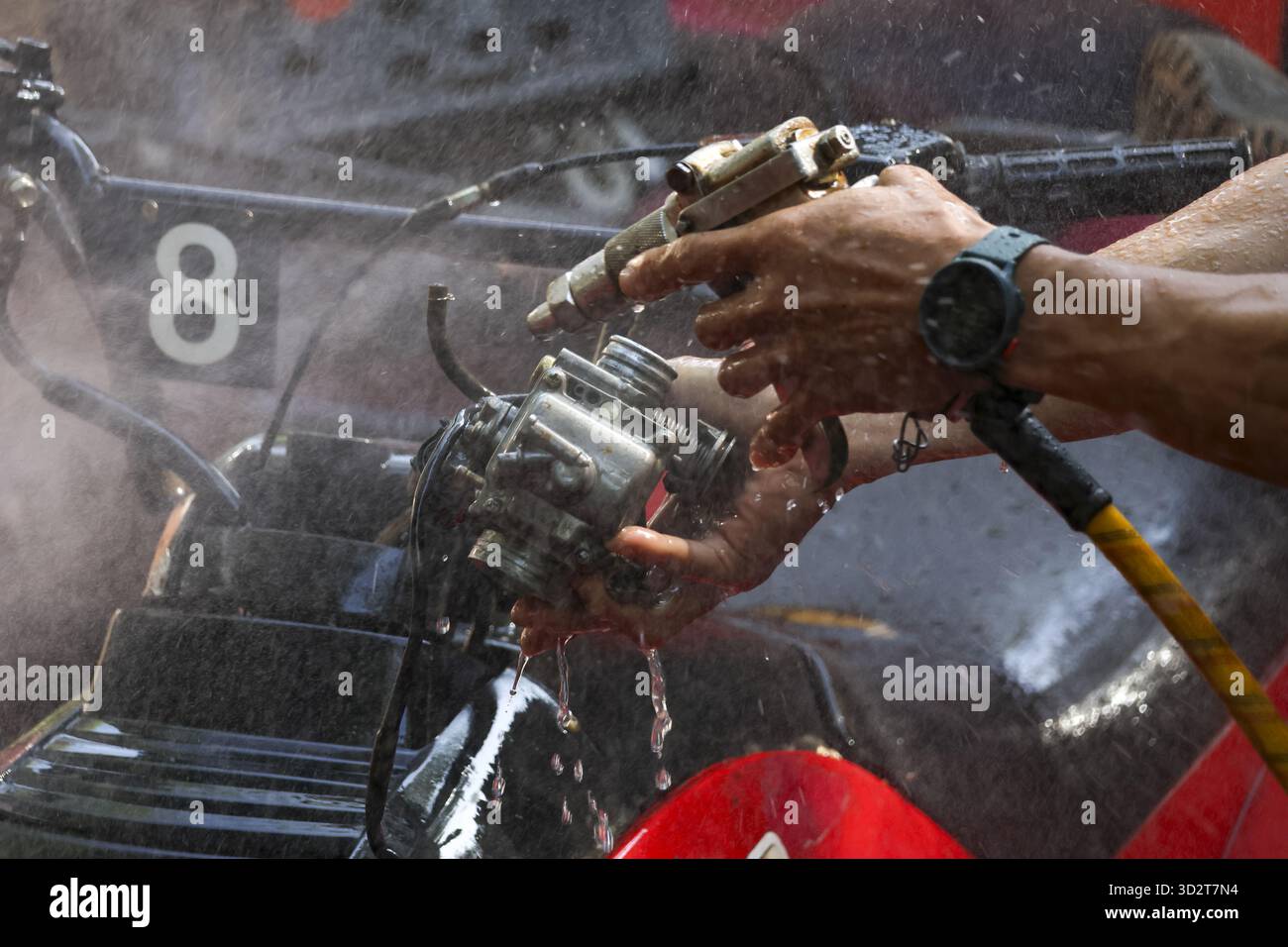 Focused mechanic hand washing race car engine with water spray. This ...