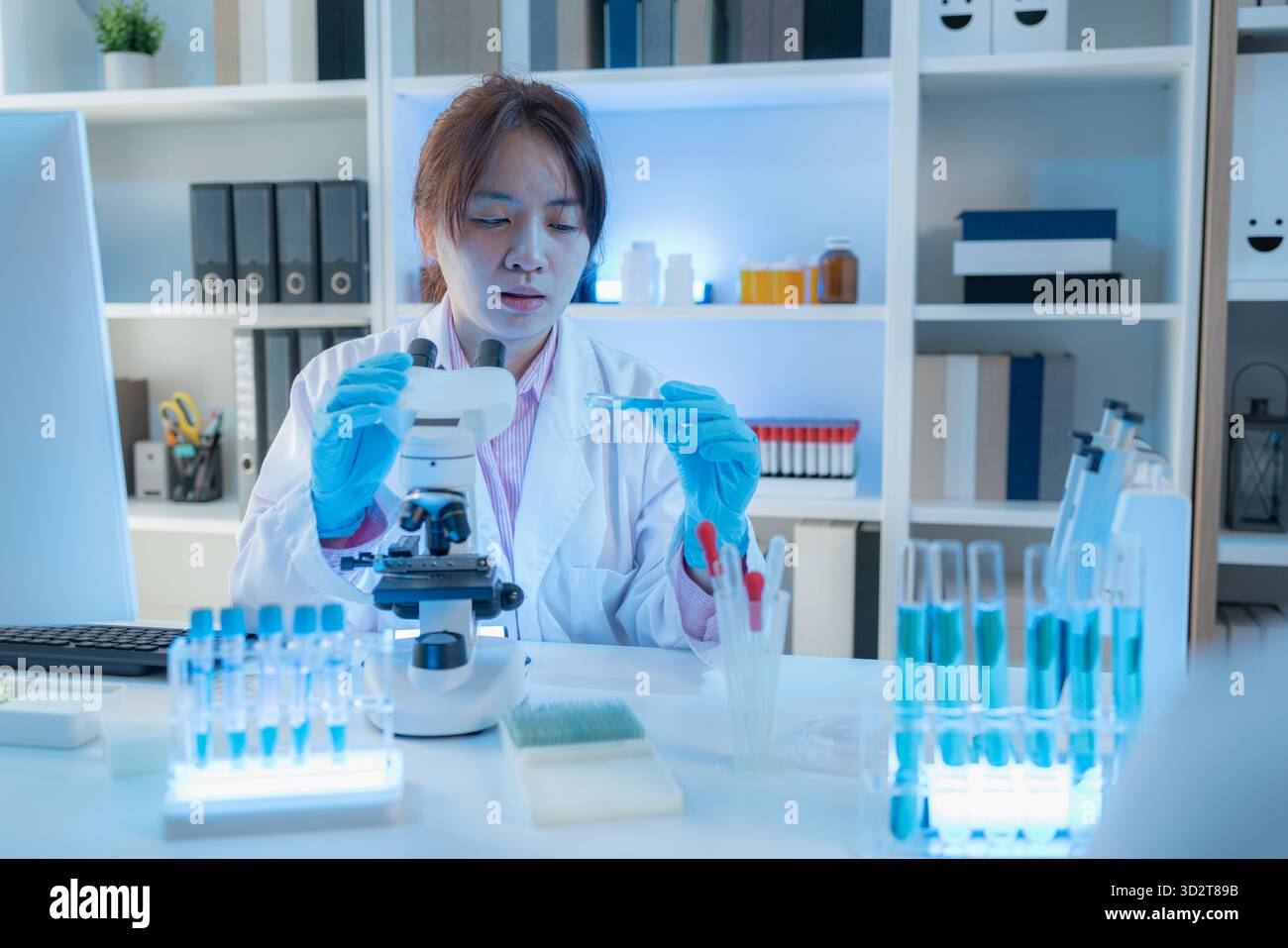 A chemistry researcher in a laboratory surrounded by scientific ...