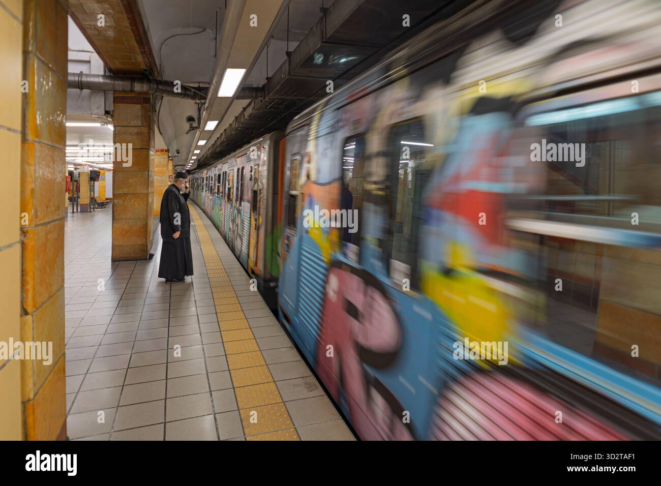 Greek Orthodox priest waits for the arrival of a train on the Athens ...