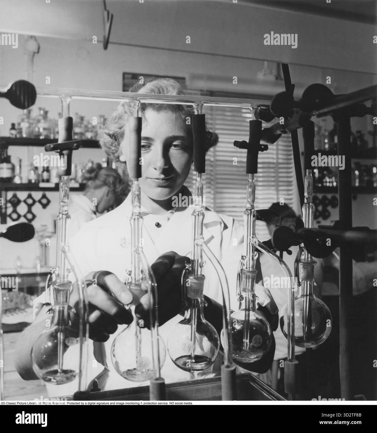 In the Laboratory, 1954. A scientist with glass tubes in a laboratory ...