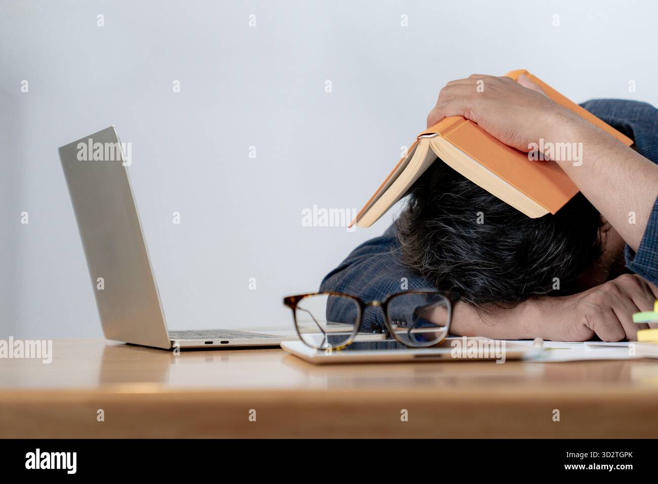 Tired young office employee fell asleep at his desk surrounded by a ...