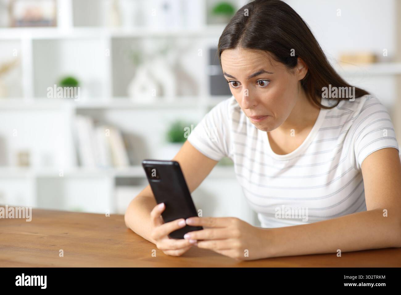 Perplexed woman checking absurd content on cell phone in a house ...