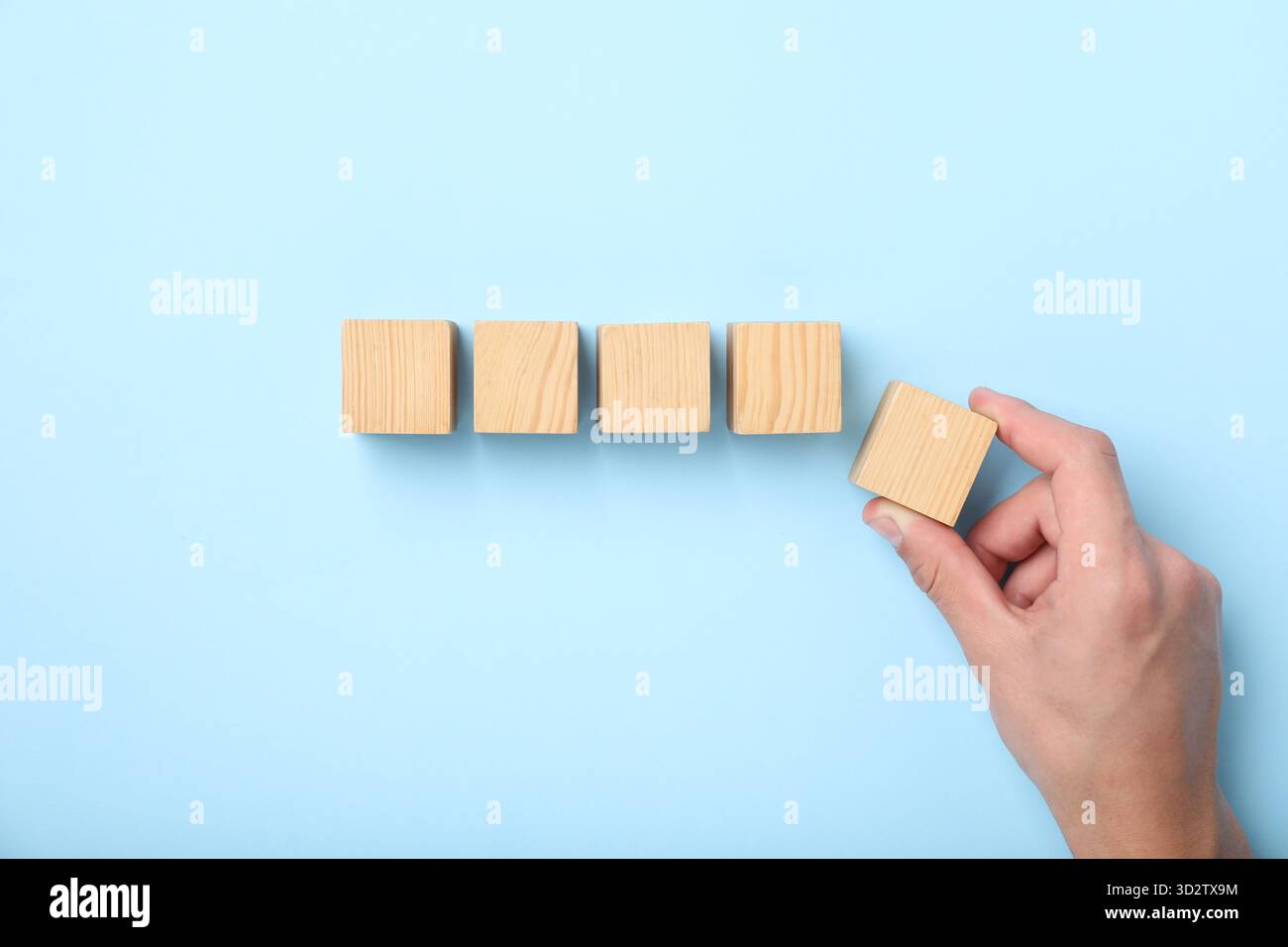 Man with wooden cubes on light blue background, top view Stock Photo ...