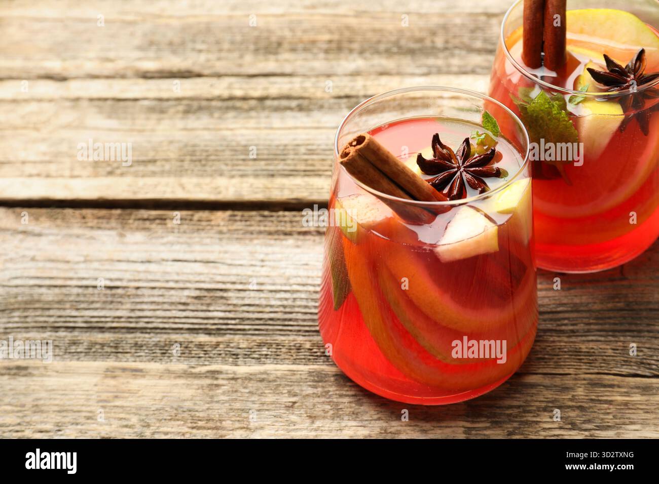 Tasty punch drink and spices in glasses on wooden table, closeup. Space ...