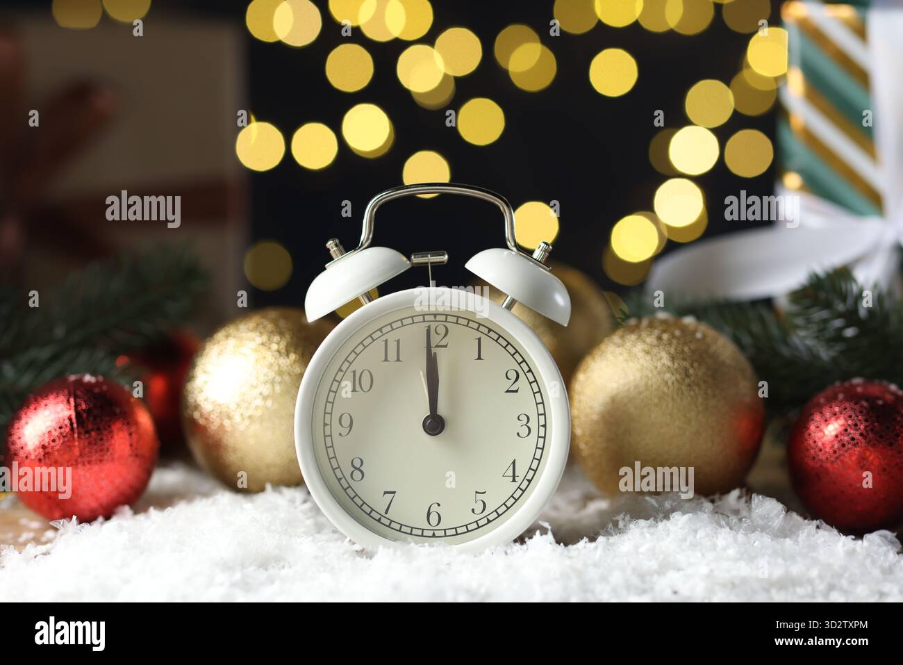New Year celebration. Alarm clock and festive decor on artificial snow ...