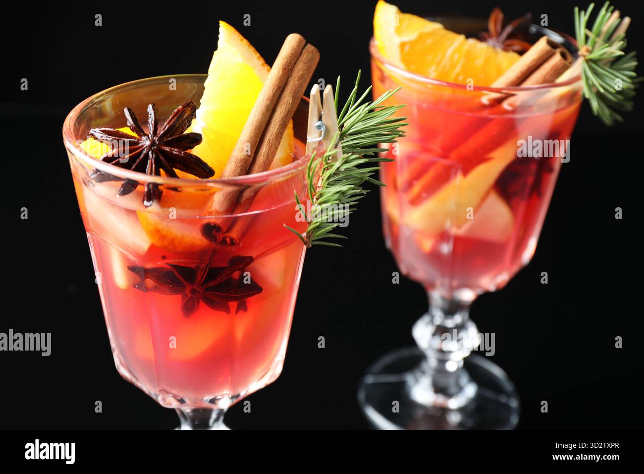 Tasty punch drink with spices in glasses on black mirror surface ...
