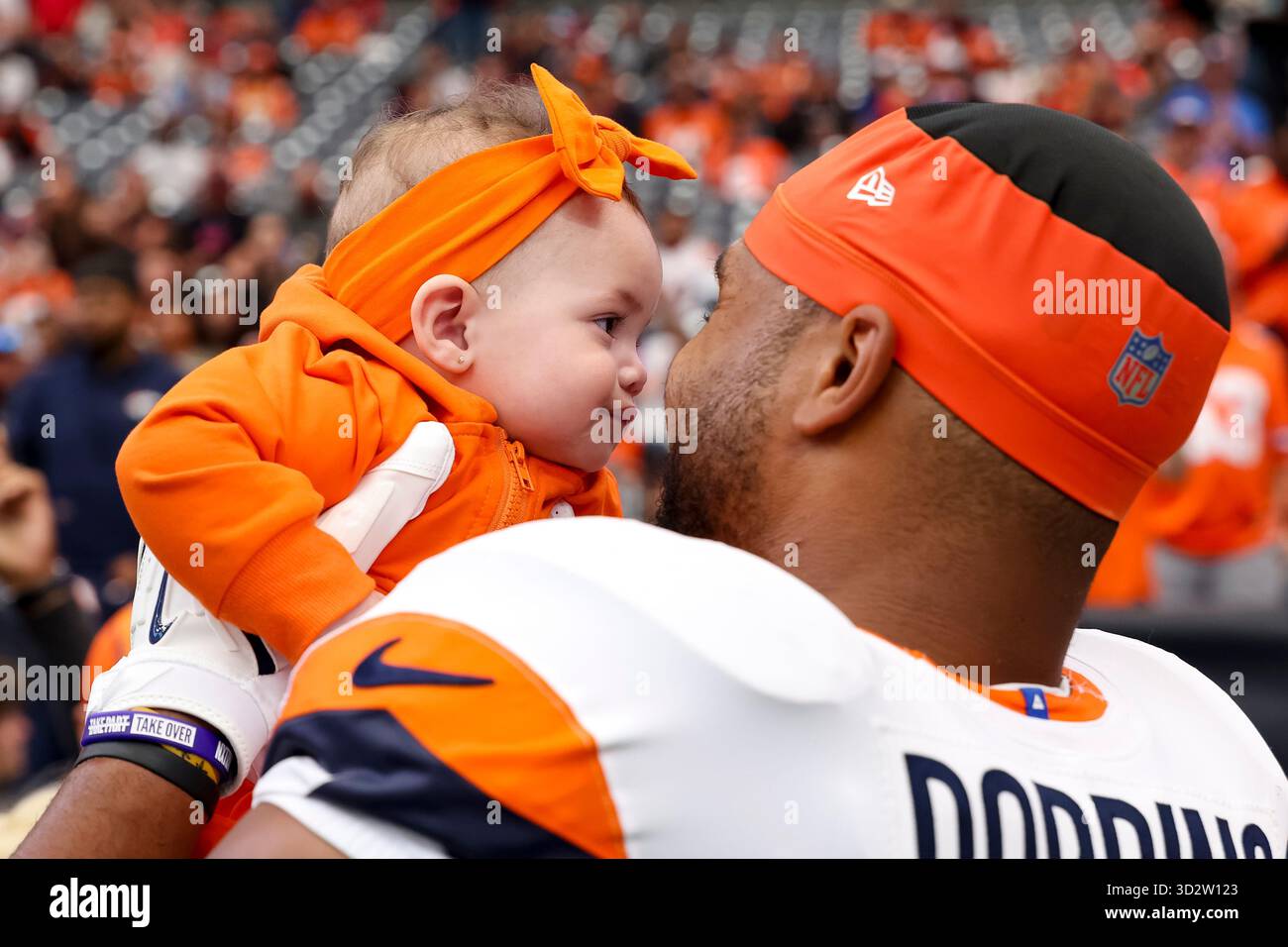 Denver Broncos running back J.K. Dobbins (27) holds his daughter prior ...