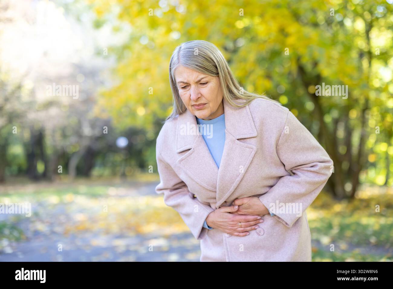 Senior woman suffering from severe abdominal pain, holding her stomach ...