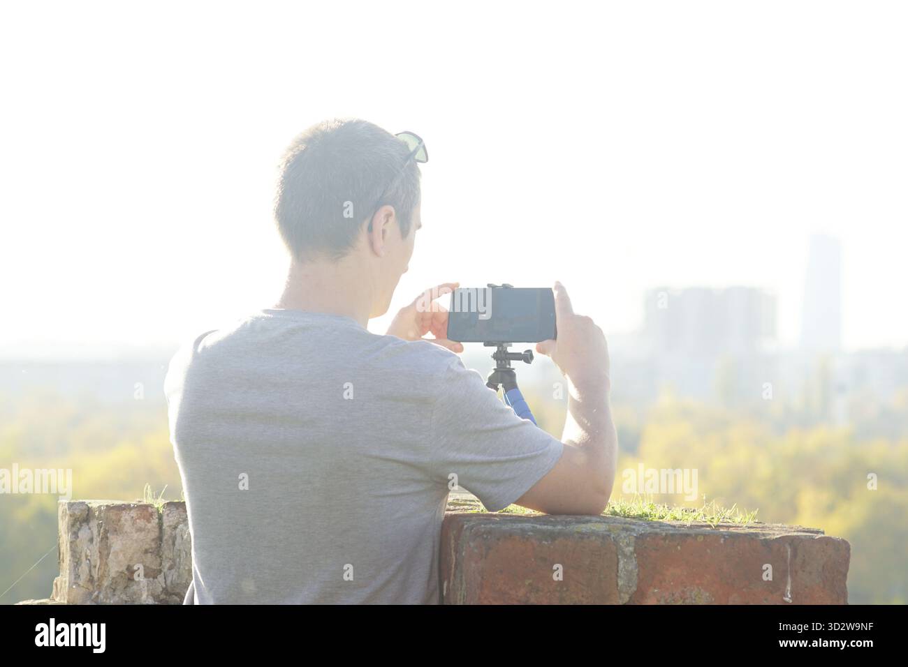 Man recording selfie video on smartphone tripod. Symbolizes content ...