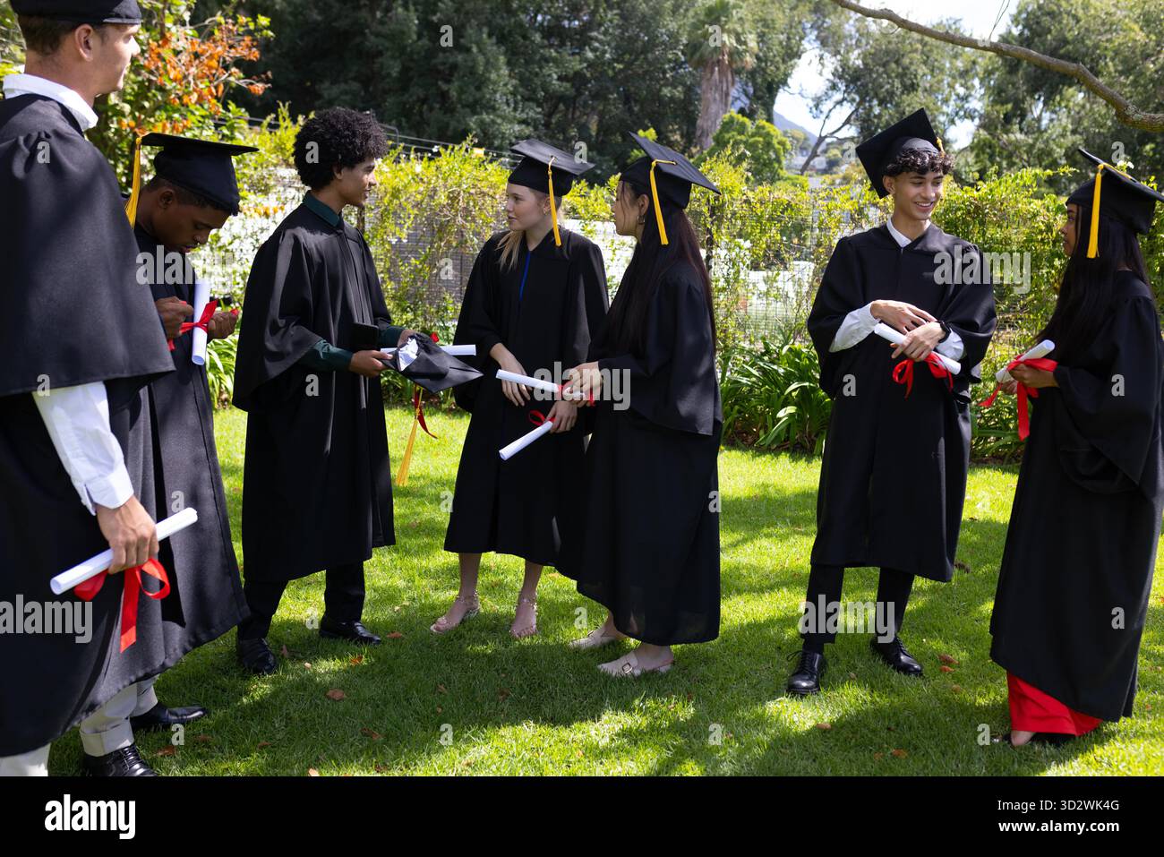 Graduating students in caps and gowns holding diplomas, celebrating ...