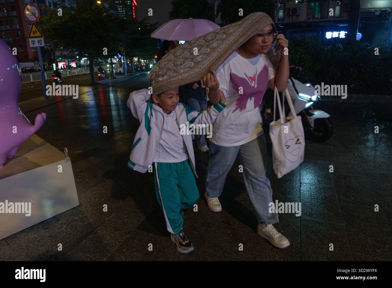 A woman and child protect themselves against the rain on the streets of ...