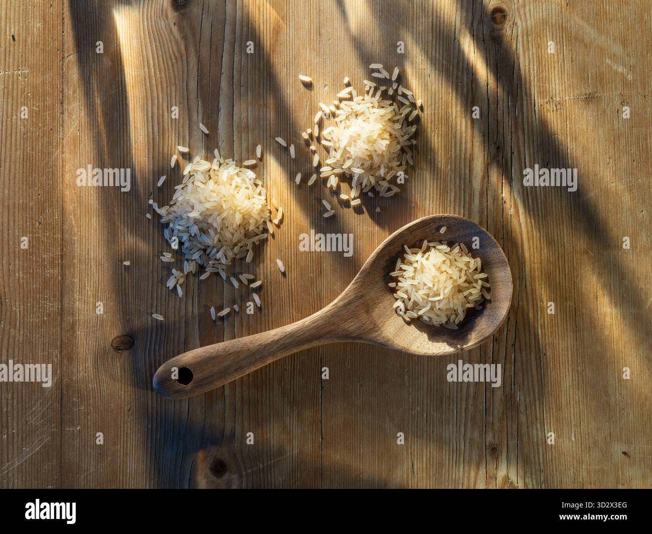 WOODEN RICE PADDLE AND LONG GRAIN RICE ON PINE TABLE TOP Stock Photo ...