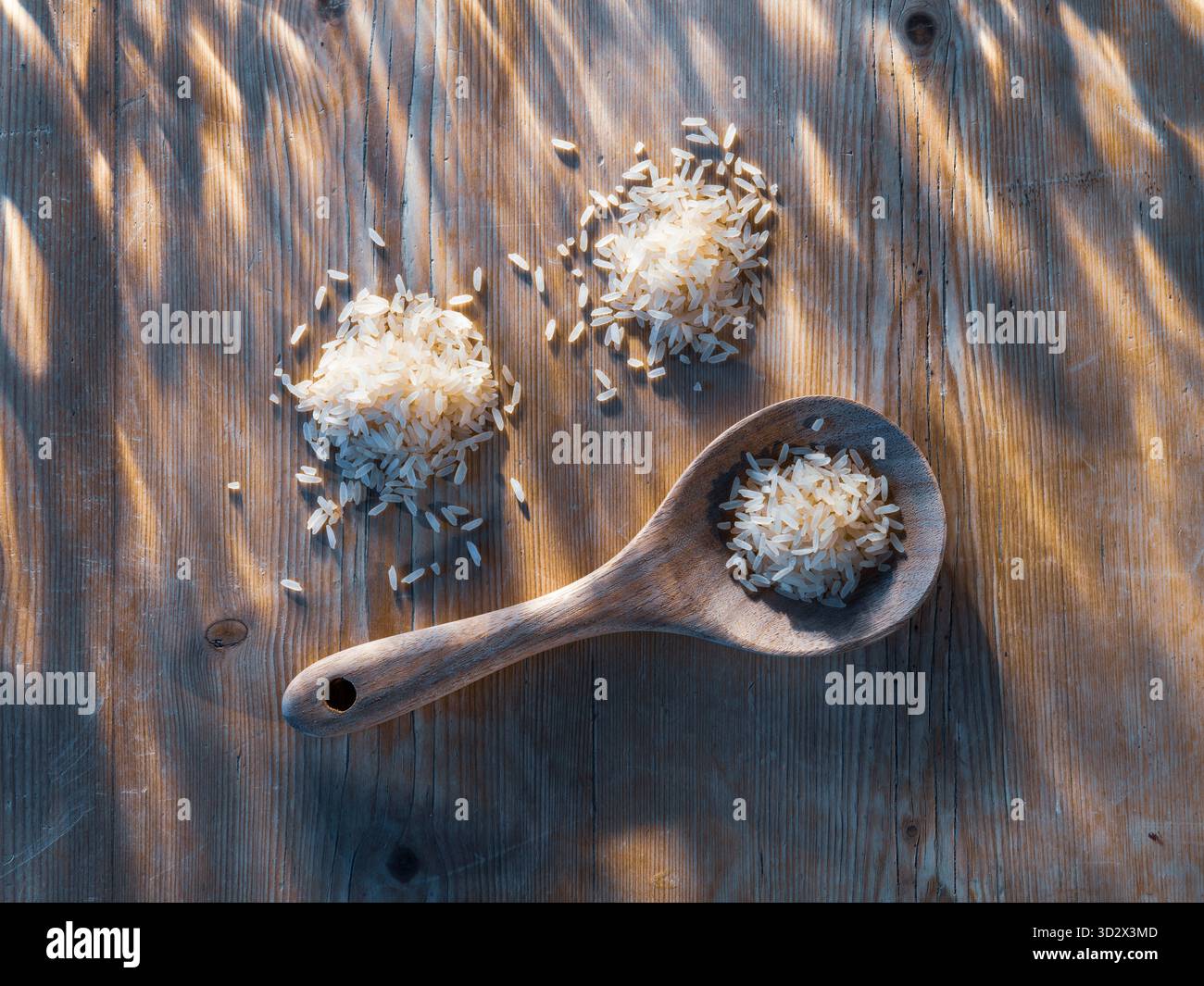 WOODEN RICE PADDLE AND LONG GRAIN RICE ON PINE TABLE TOP Stock Photo ...