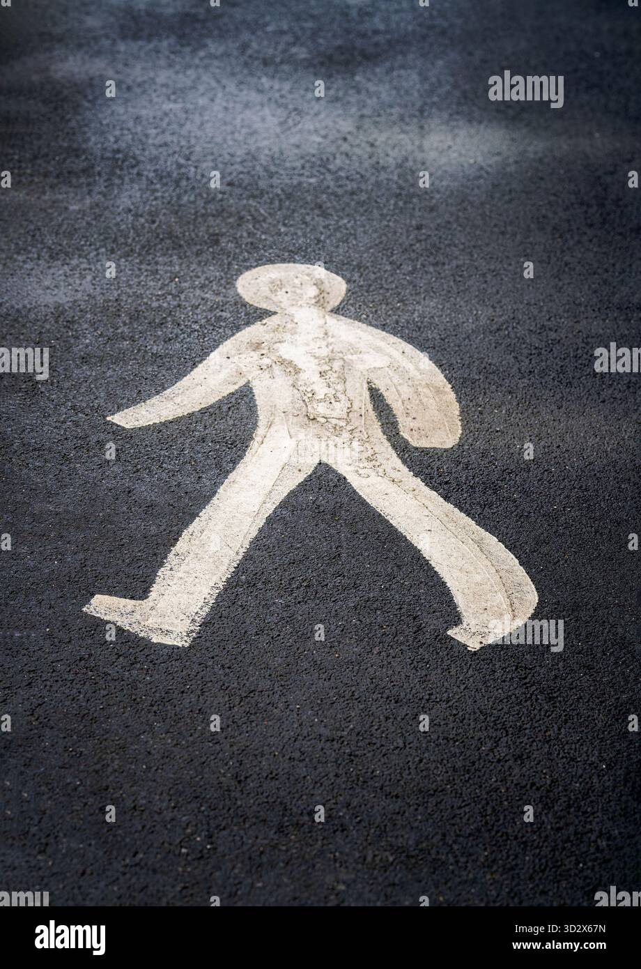 A white painted symbol of a man walking on a tarmac road, indicates the ...