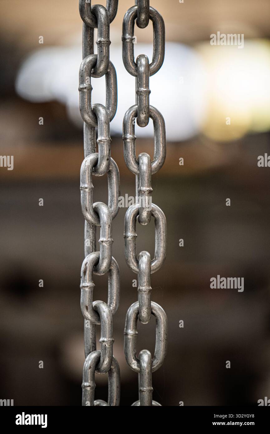 A chain of silver links is shown in a close up. The chain is long and ...