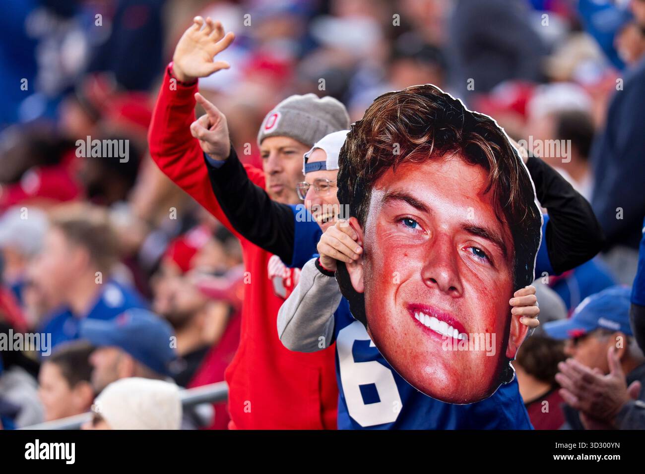 Fans hold up a big head of New York Giants quarterback Jaxson Dart (6 ...