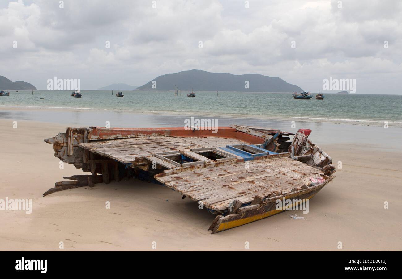 Abandoned wooden fishing boat wreck on a wide sandy beach in Con Dao ...