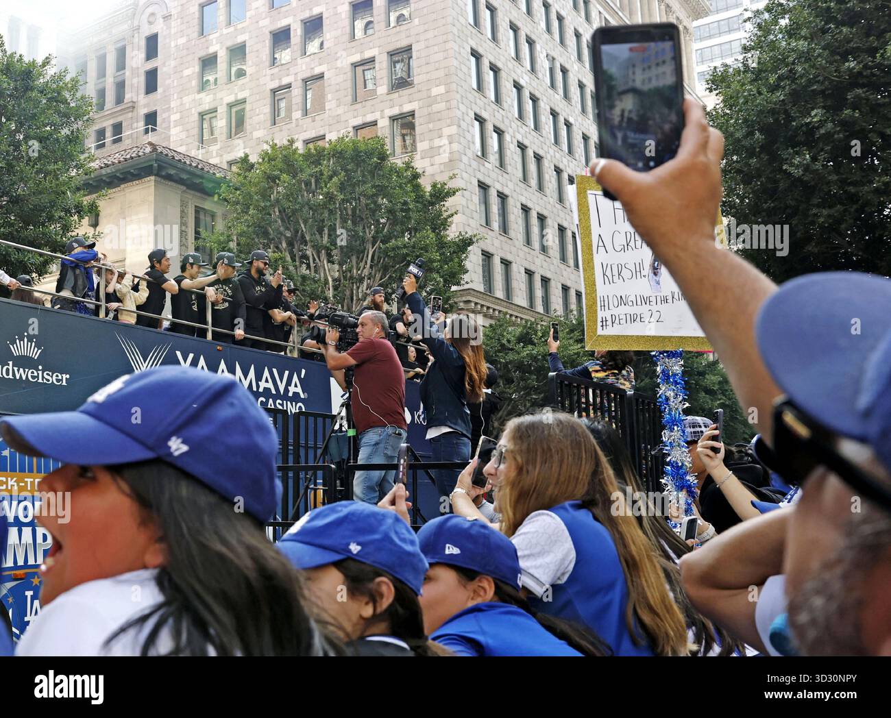 Fans watch Los Angeles Dodgers players standing on an open-top bus ...