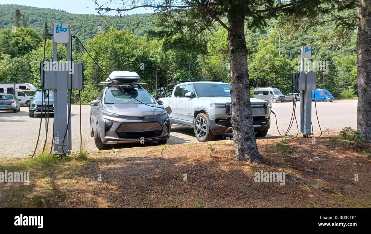 Quebec, QC, Canada - July 31, 2025 - Electric vehicles charge at a station in a scenic park ...