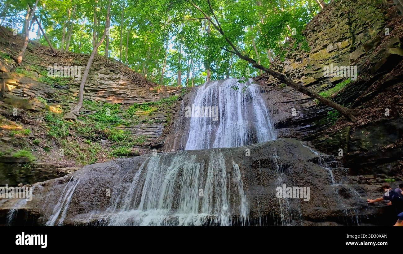 A beautiful waterfall cascades down tiered rock formations in a lush ...