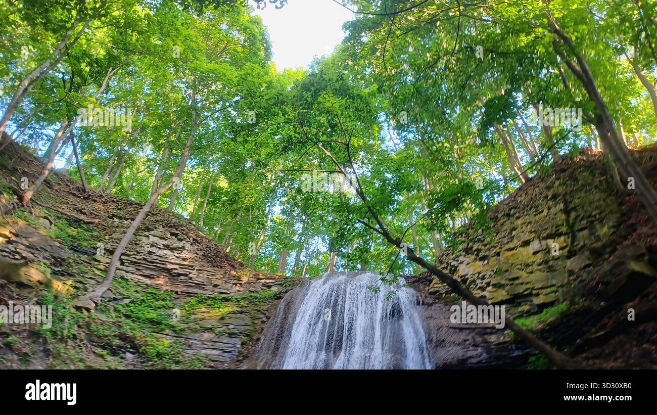 A beautiful waterfall cascades down tiered rock formations in a lush ...