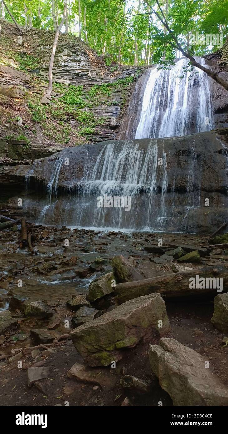 A beautiful waterfall cascades down tiered rock formations in a lush ...