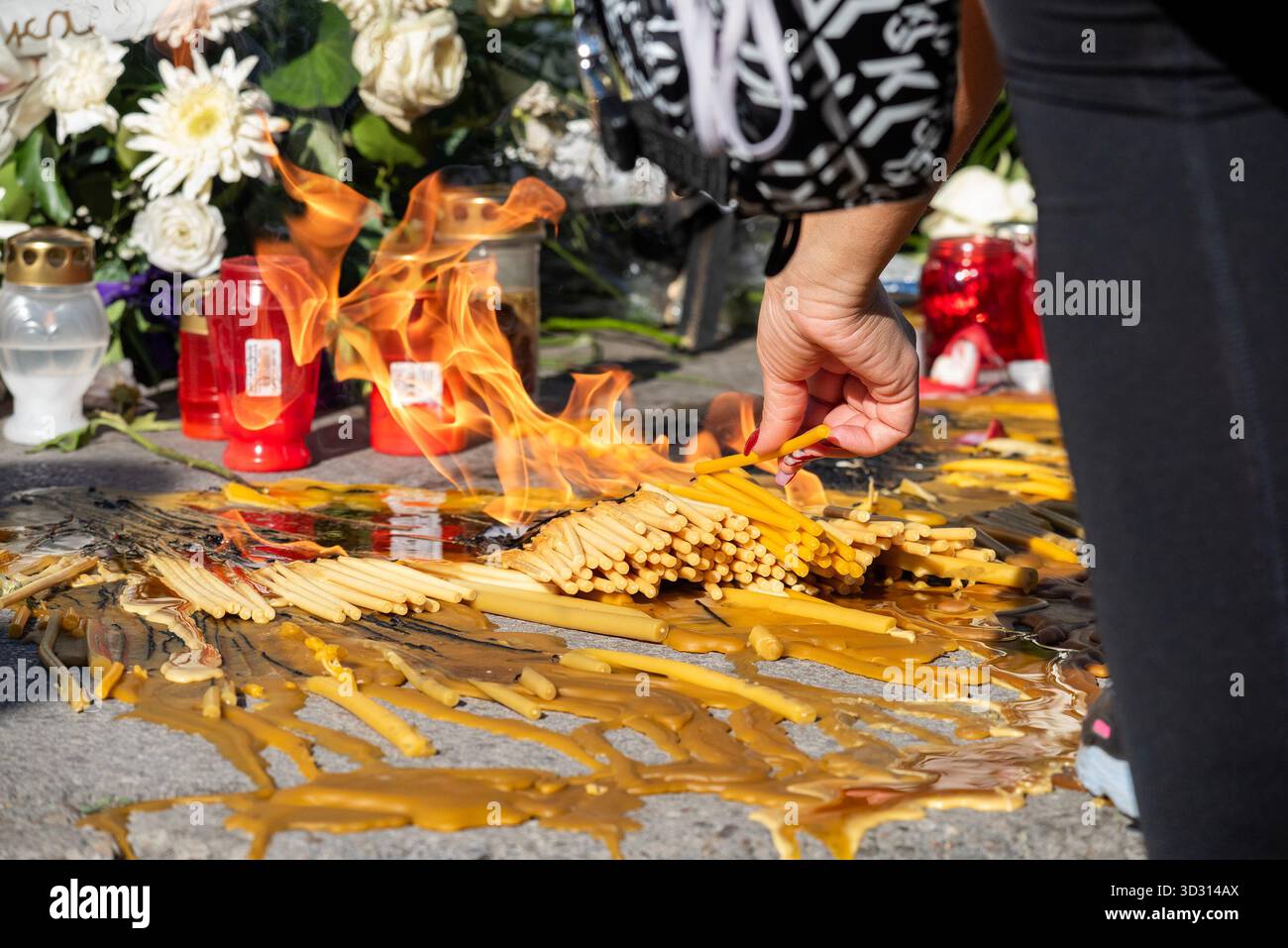 A mourner lights up a candle for the memories of the victims outside ...