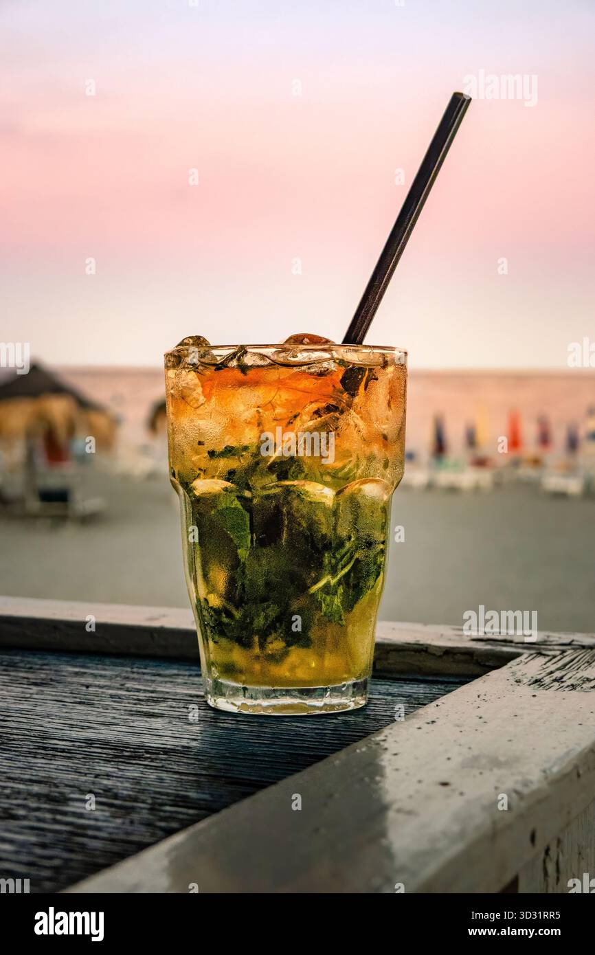 A refreshing mojito cocktail with mint and ice sits on a wooden beach ...