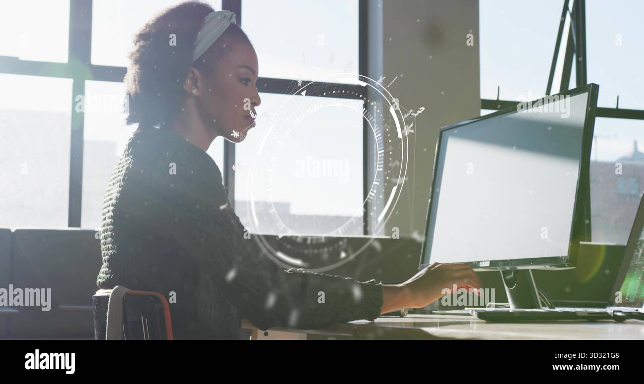 Analyzing woman wearing sweater at desk in office, viewing monitors ...