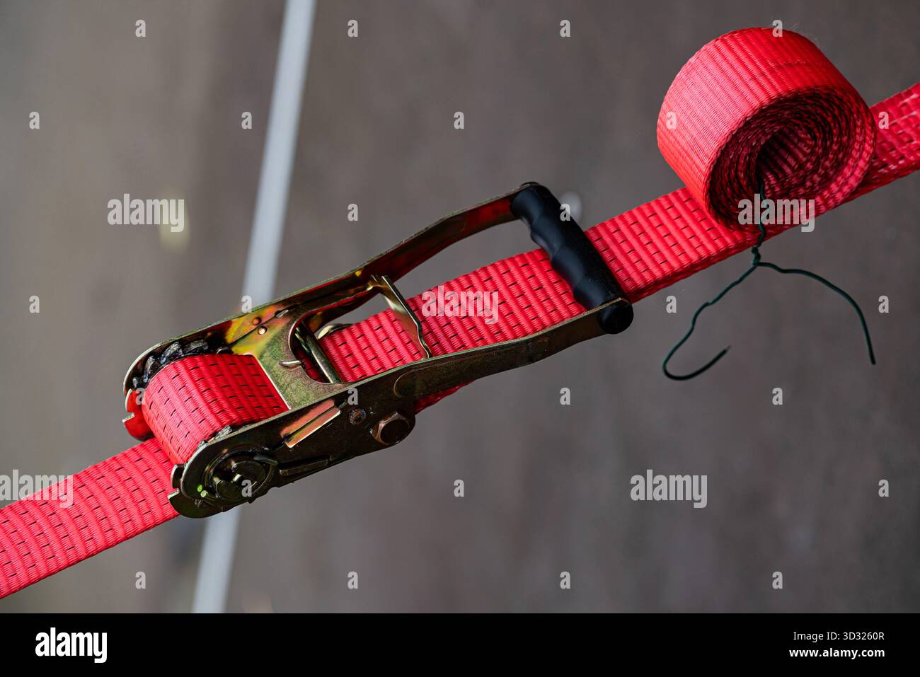 A bright red ratchet strap is shown being used to secure items tightly ...