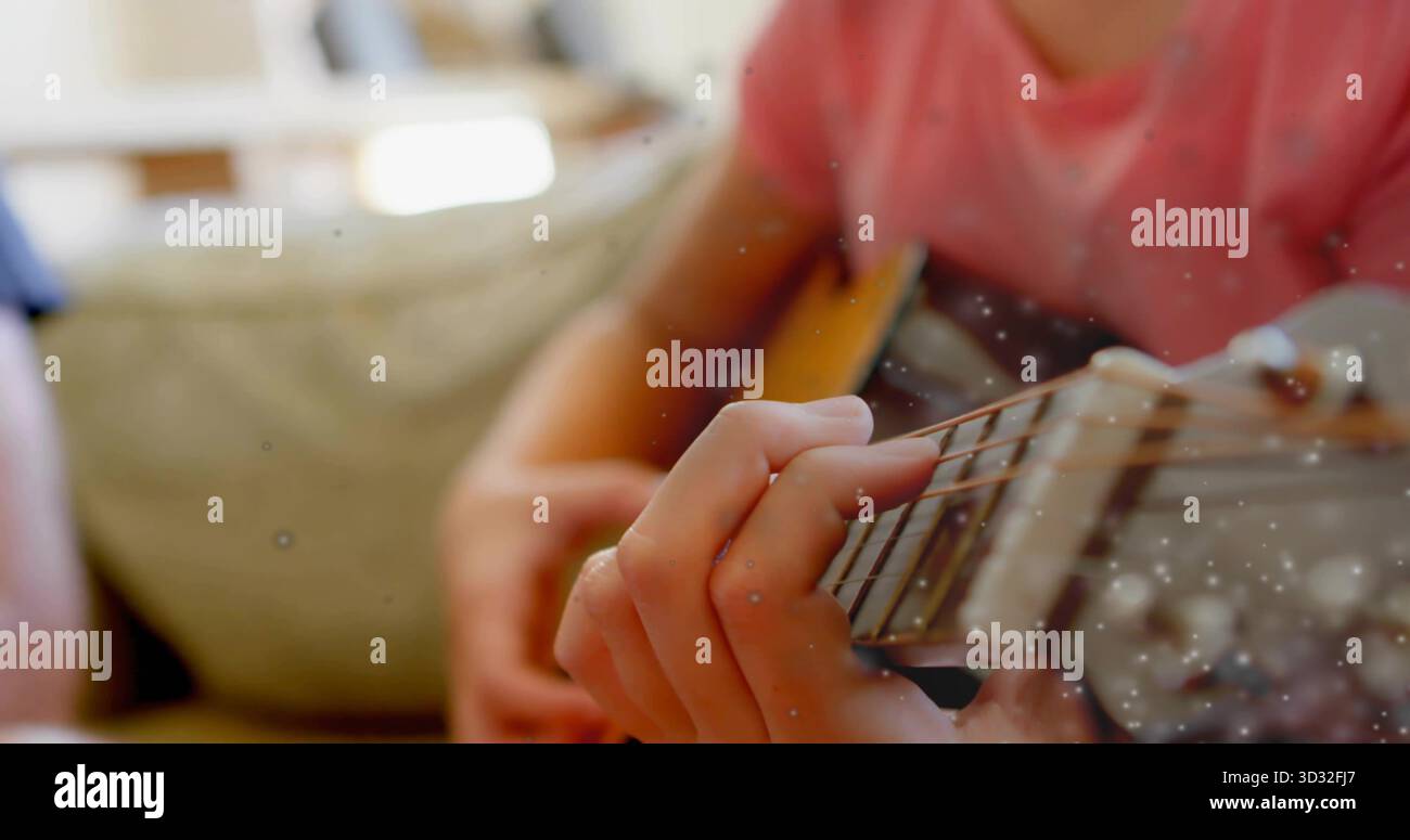Playing girl pressing chords on acoustic guitar on sofa in living room ...