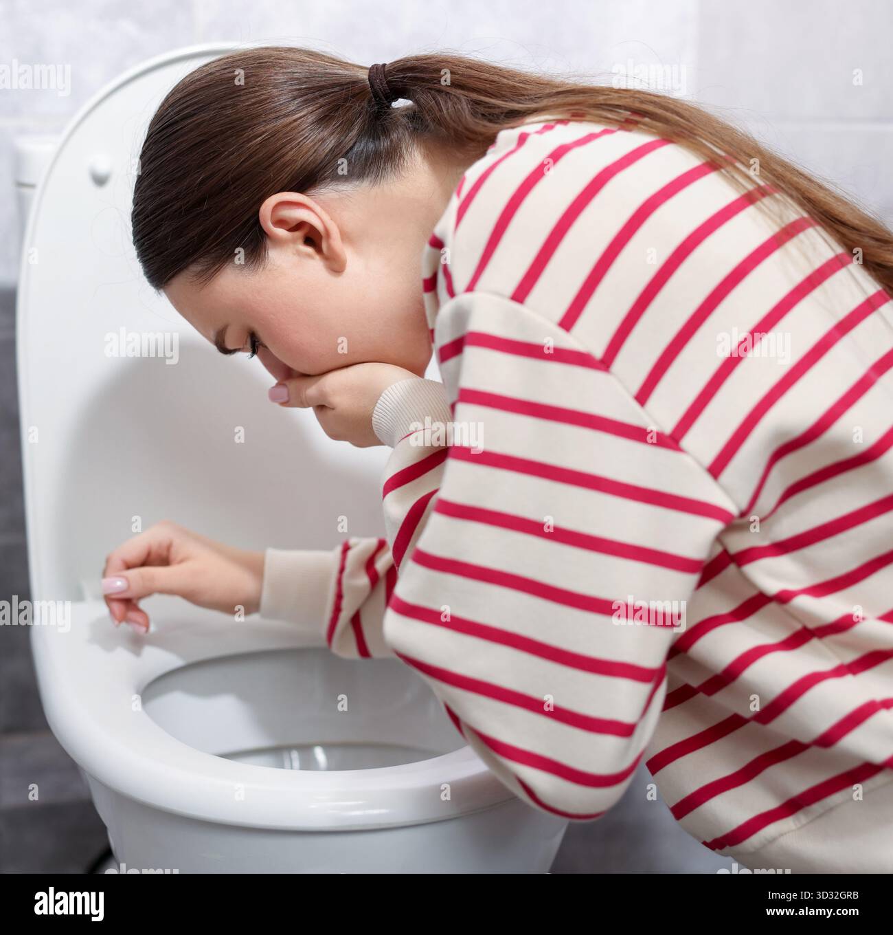 Woman suffering from nausea over toilet bowl in bathroom Stock Photo ...