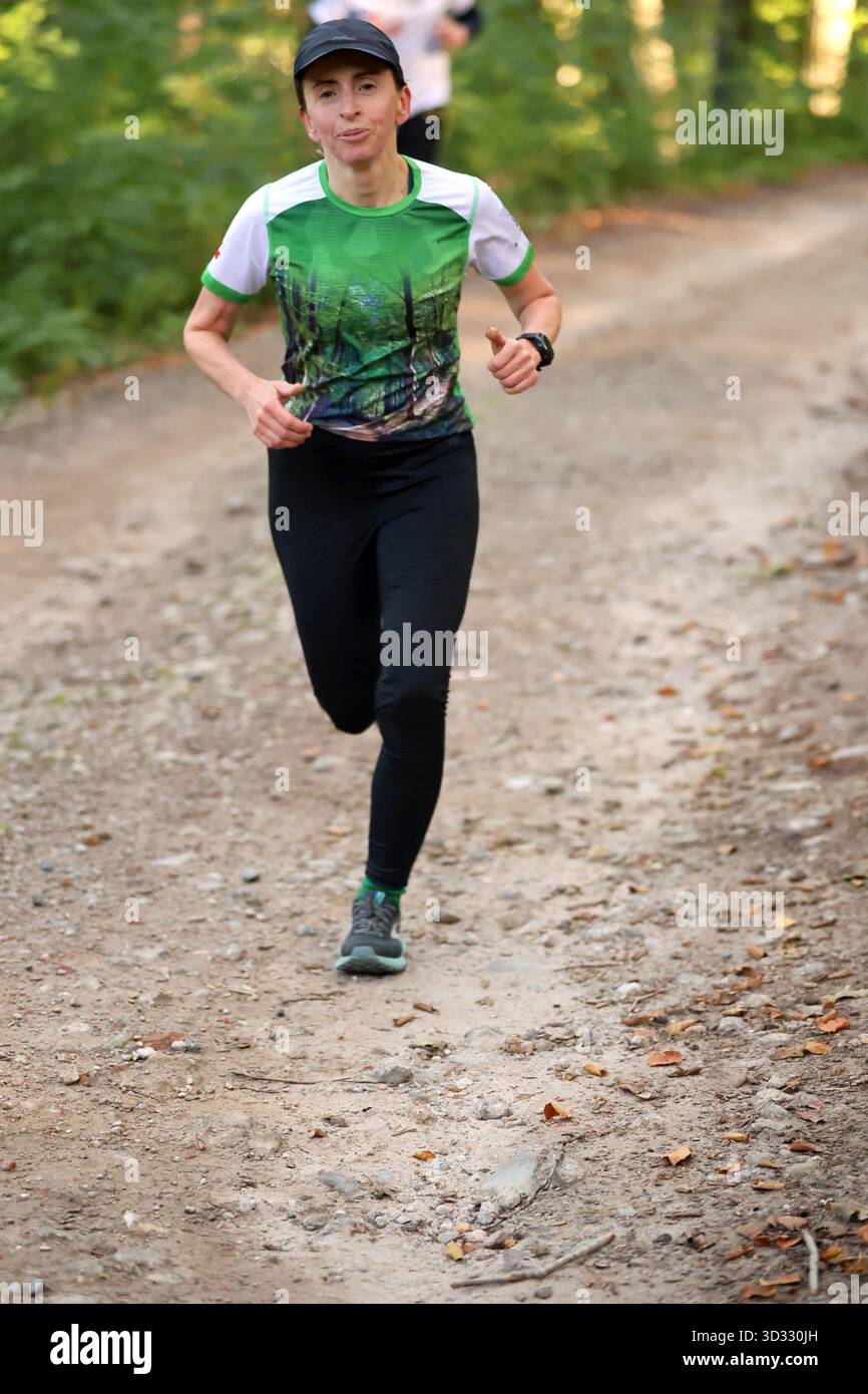 Focused female athlete trail running through a natural forest path ...