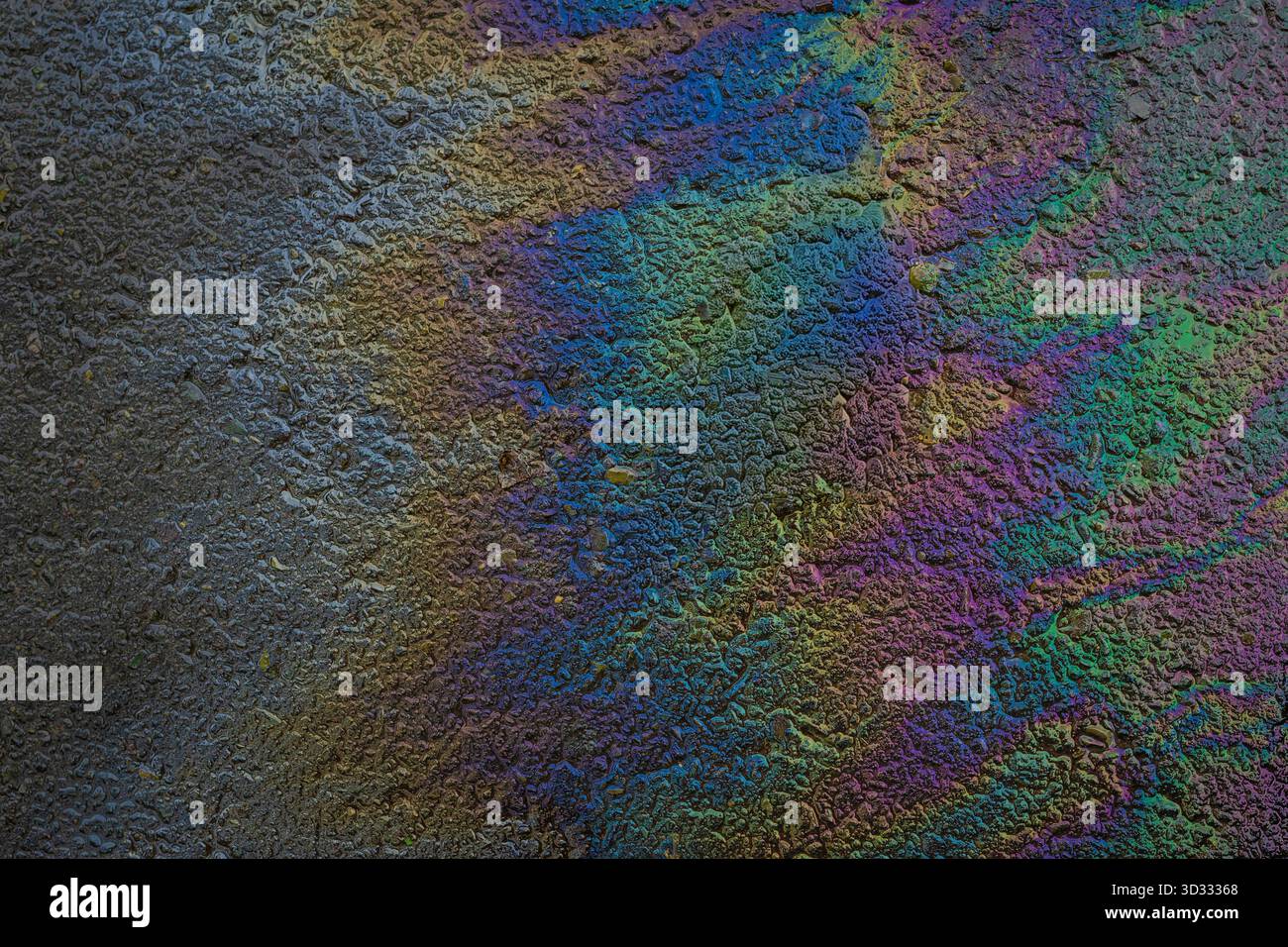 Colorful oil spill on wet asphalt creates vibrant rainbow texture with ...