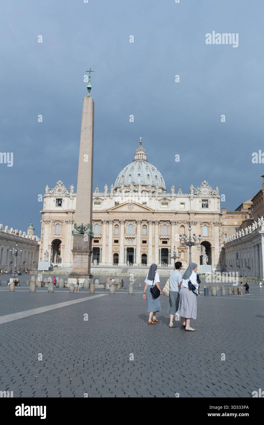 Nuns walk through St. Peters Square and St. Peter's Basilica on a dark ...