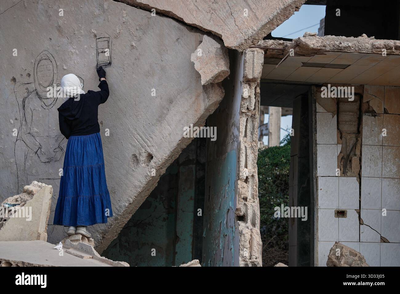 A Syrian graffiti artist sketches a mural on the collapsed ceiling of a ...
