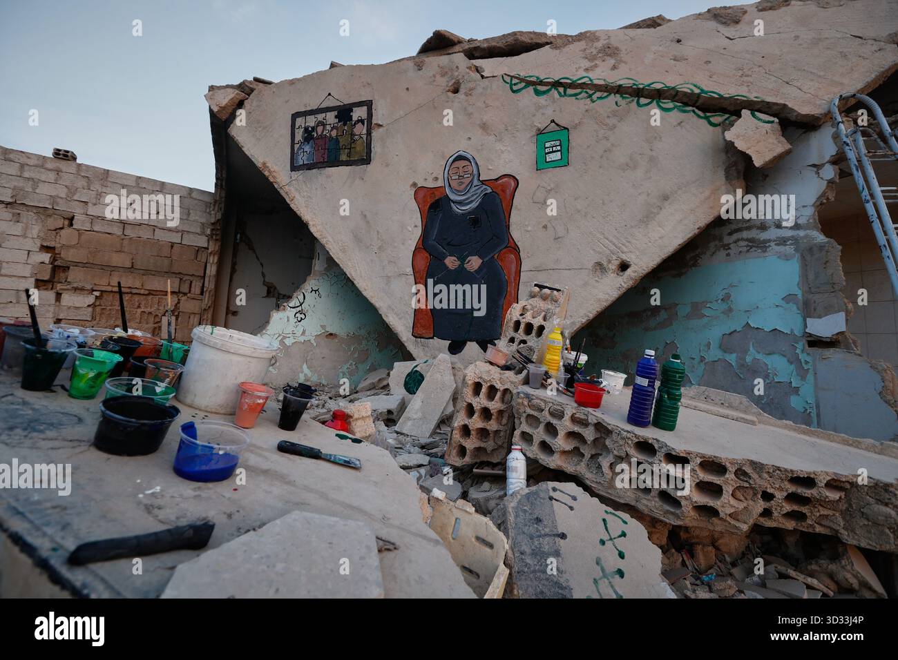 Paint and brushes sit on rubble next to a graffiti mural recently ...