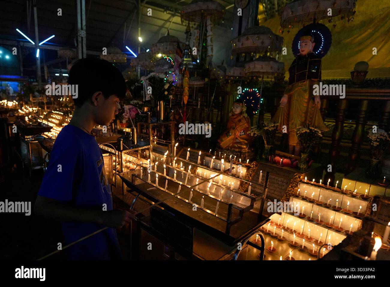 Buddhist devotee lights candles during the full moon day of Tazaungmone, also known as lighting ...