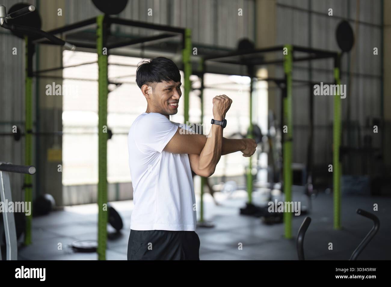 A smiling young man stretches his arms, promoting wellness and ...