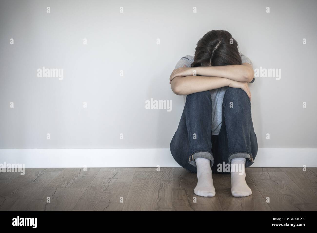 Sad woman sitting on a floor alone in empty room, despair and lonely ...