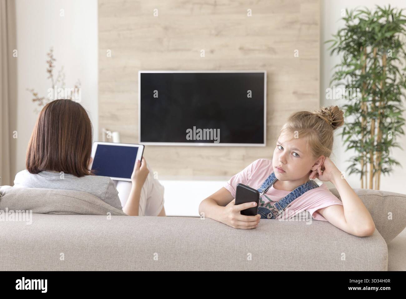 Girl sitting on couch and watching something interesting in mobile ...