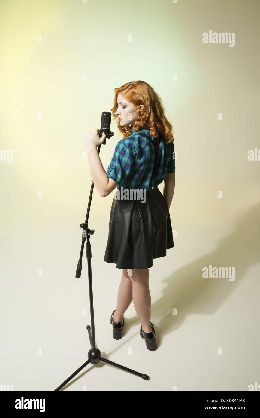 Back view of red-haired singer with mic.Studio shot Stock Photo - Alamy