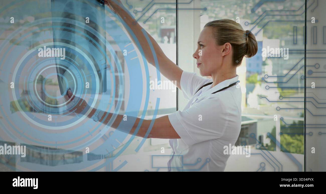 Female doctor examining X-ray film at radiology room window, with ...