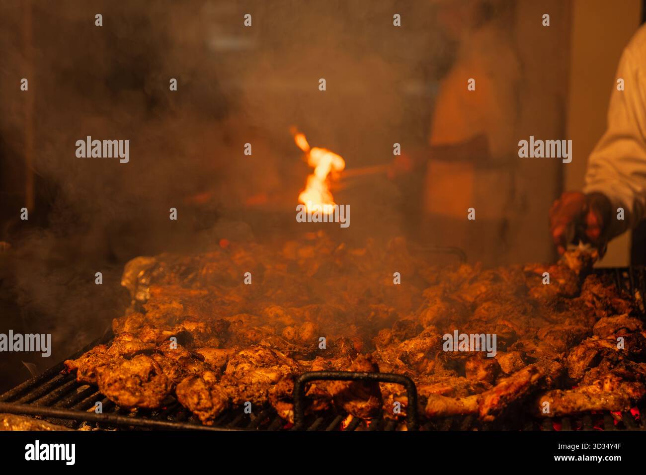 A close-up of marinated chicken being grilled over an open flame, with ...