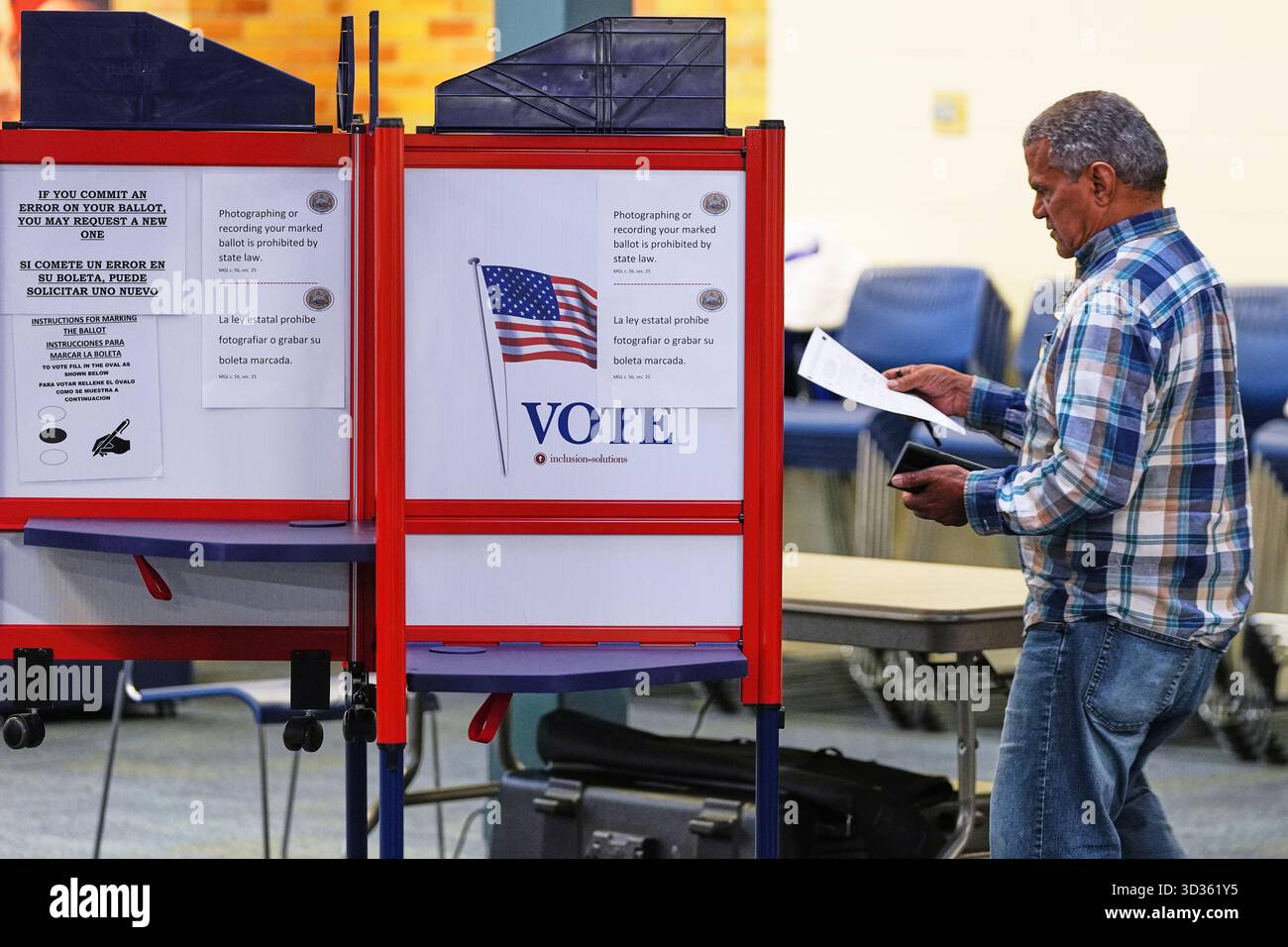 A voter carries his ballot to a booth at a polling station, Tuesday ...