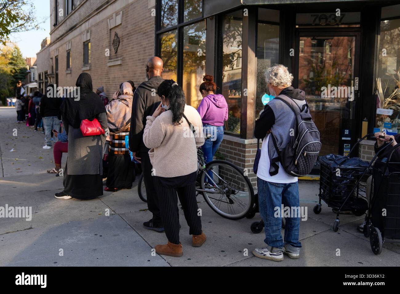 Clients wait in line to collect groceries at the Ignatian Mission ...